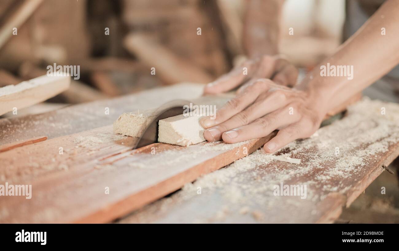 close up of a carpenter's hand cutting wood planks using a circle saw ...