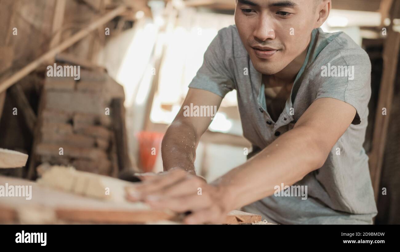 The carpenter is sitting holding the wood while cutting with a circular ...