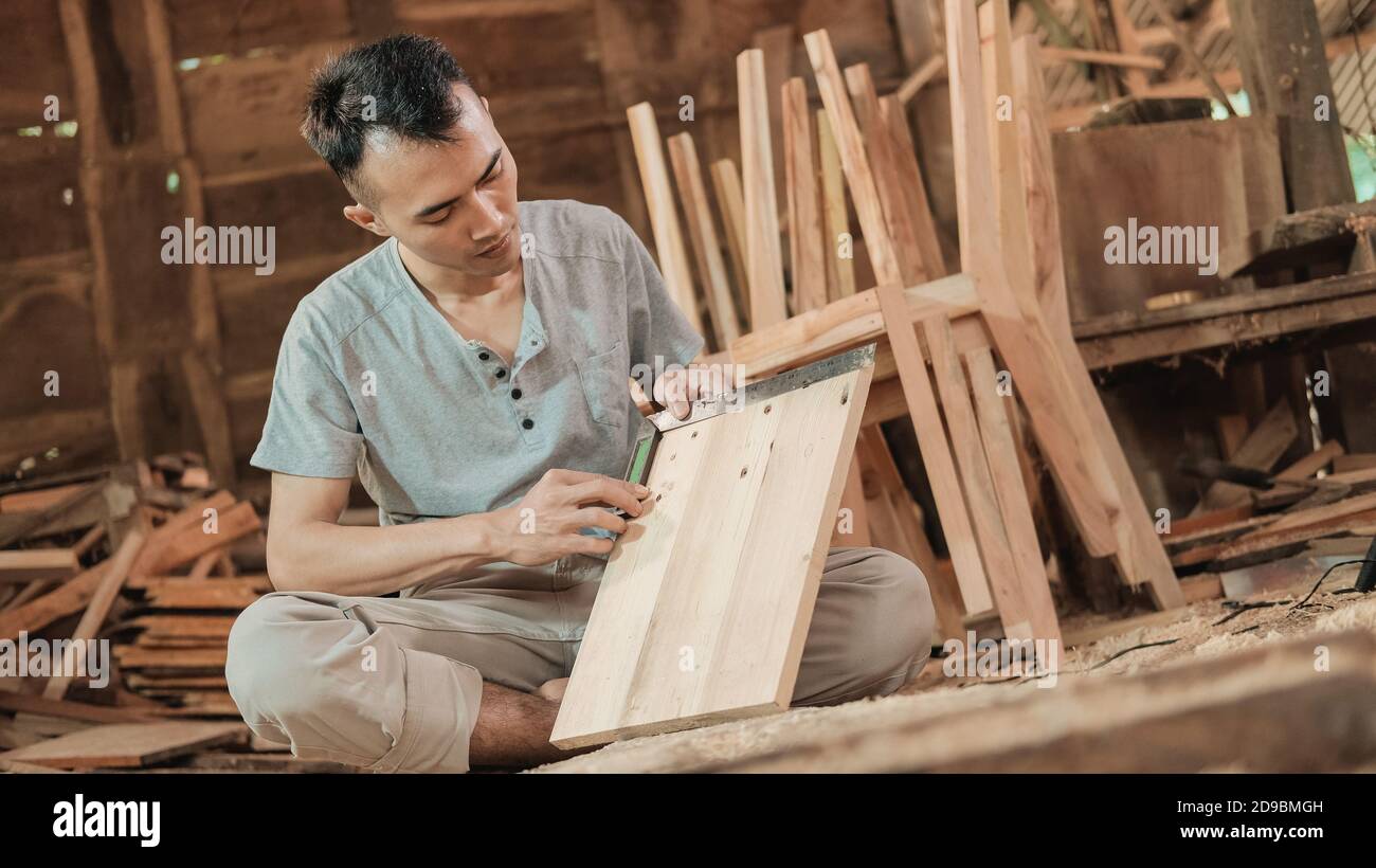 carpenter sitting on the floor holding a carpenter elbow ruler while ...
