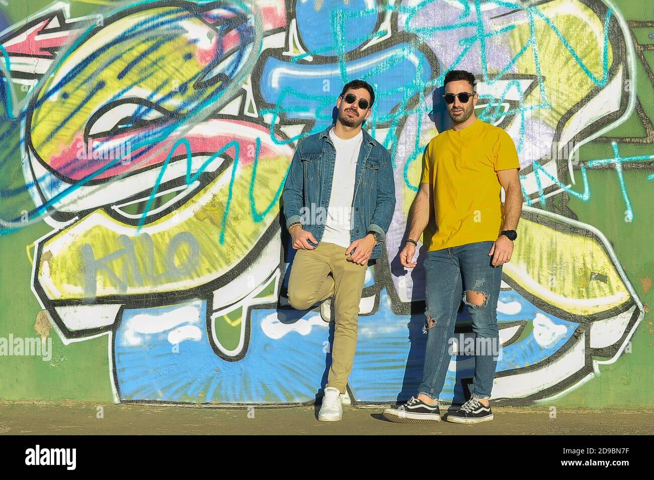 Friends having fun graffiti wall background Stock Photo - Alamy