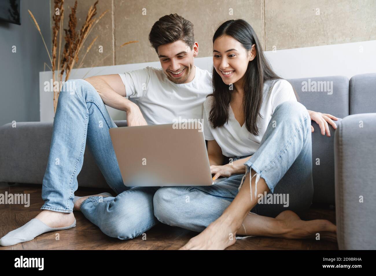 Photo of a cheerful young loving couple at home on floor near sofa ...