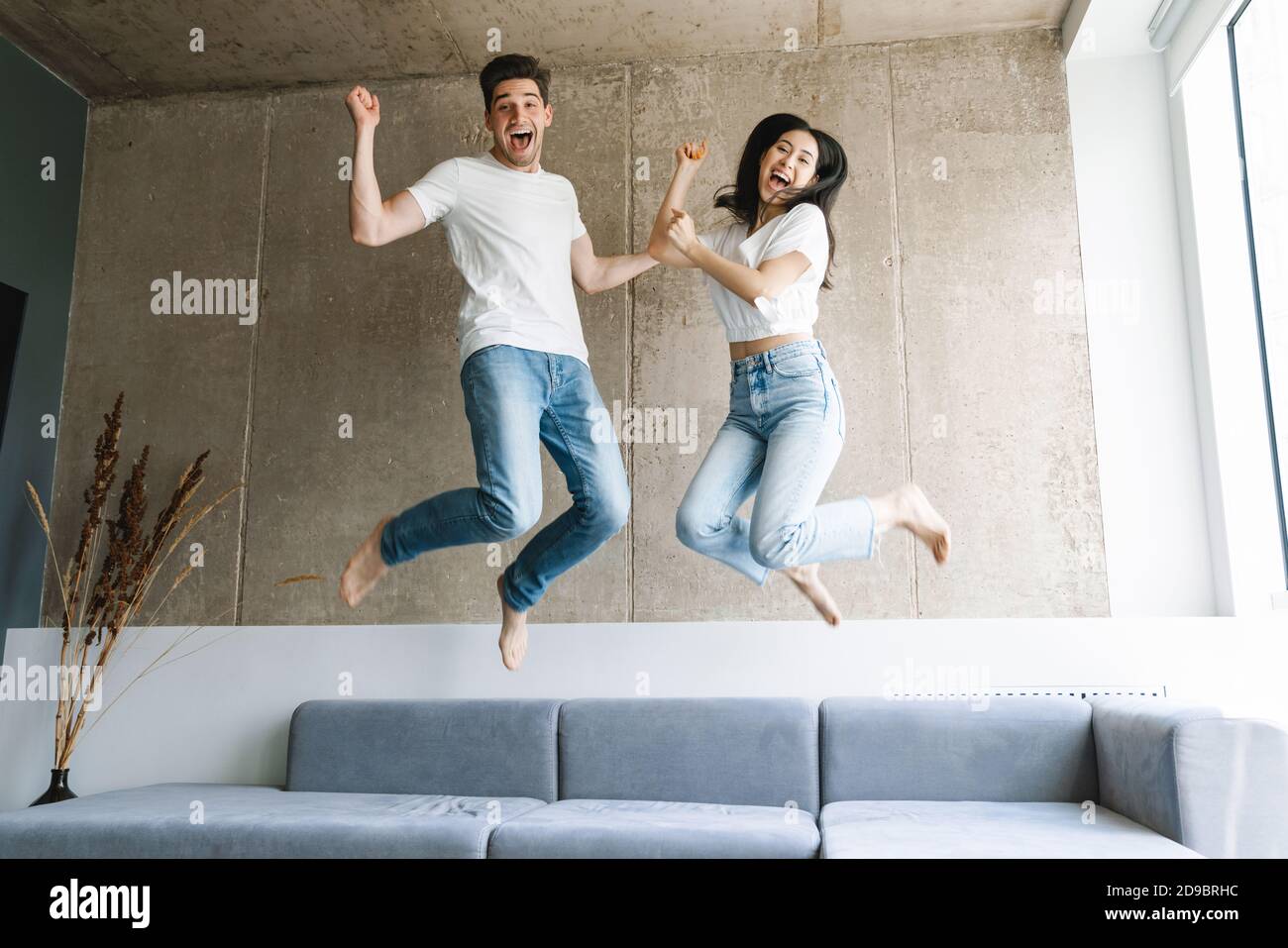 Young woman jumping on sofa hi-res stock photography and images - Alamy