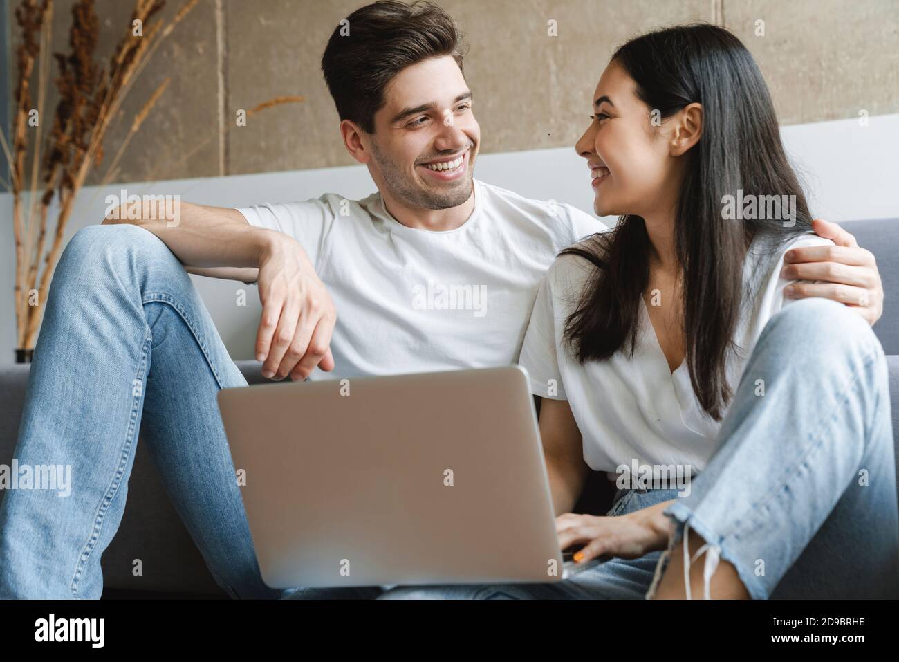 Photo of a cheerful young loving couple at home on floor near sofa ...