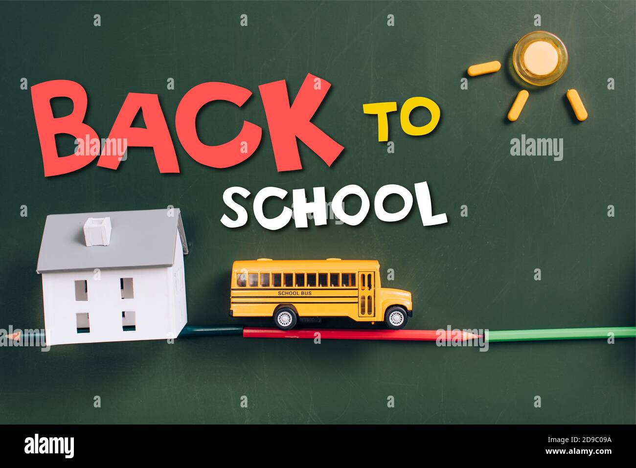 top view of toy school bus on road made of color pencils, house model ...