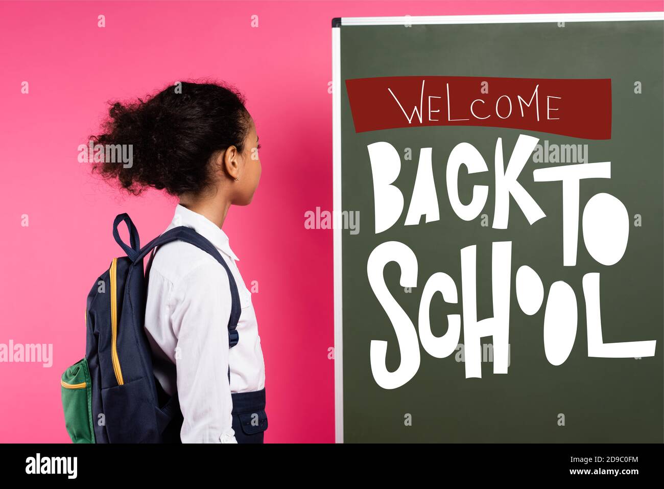 african american schoolkid looking at chalkboard with welcome back to ...