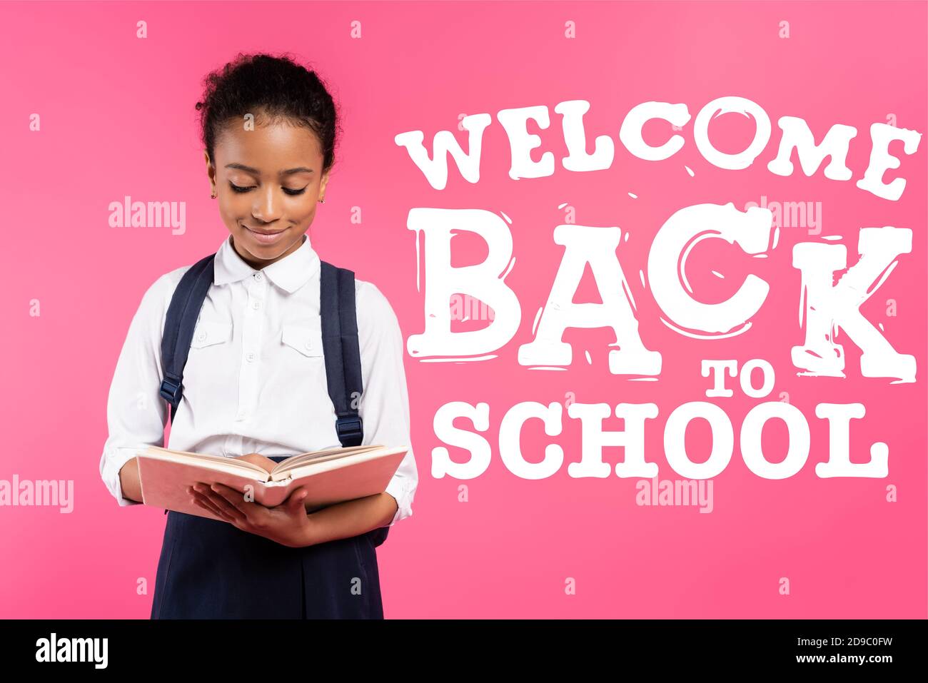 african american schoolgirl reading book near welcome back to school ...