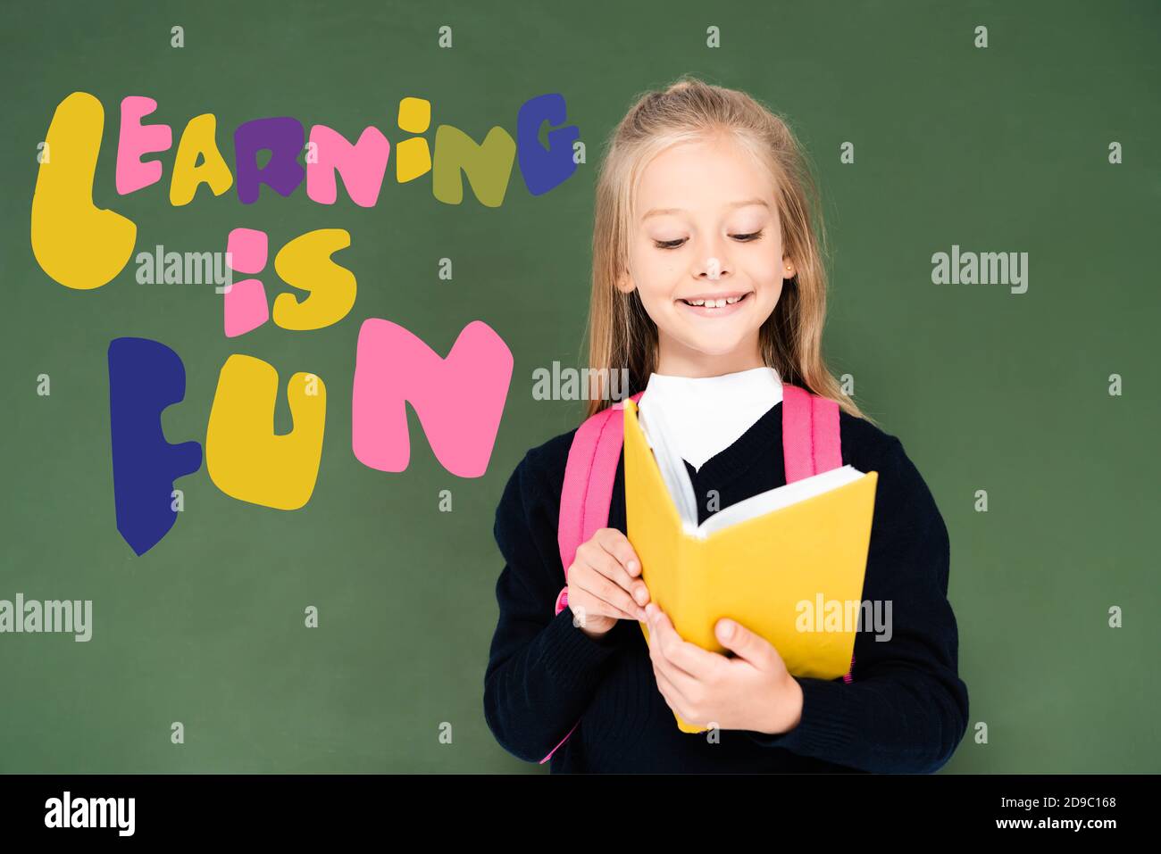 schoolgirl reading book near green chalkboard with learning is fun ...