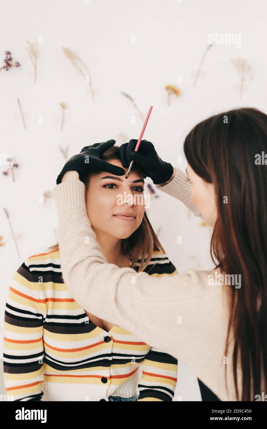 Eyebrow shaping procedure, make-up master uses brush to shape the ...