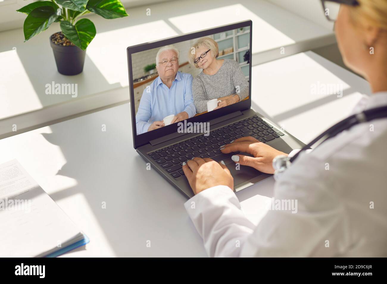 Faceless doctor sitting in her office and talking to a senior couple ...