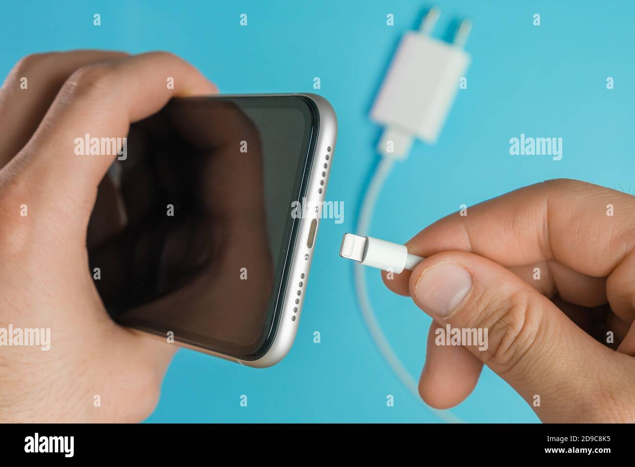 Close up mans hand inserting a charger into the mobile phone through a ...