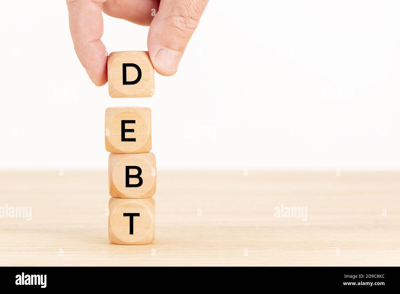 Debt concept. Hand holding a pile of Wooden blocks on table. White ...