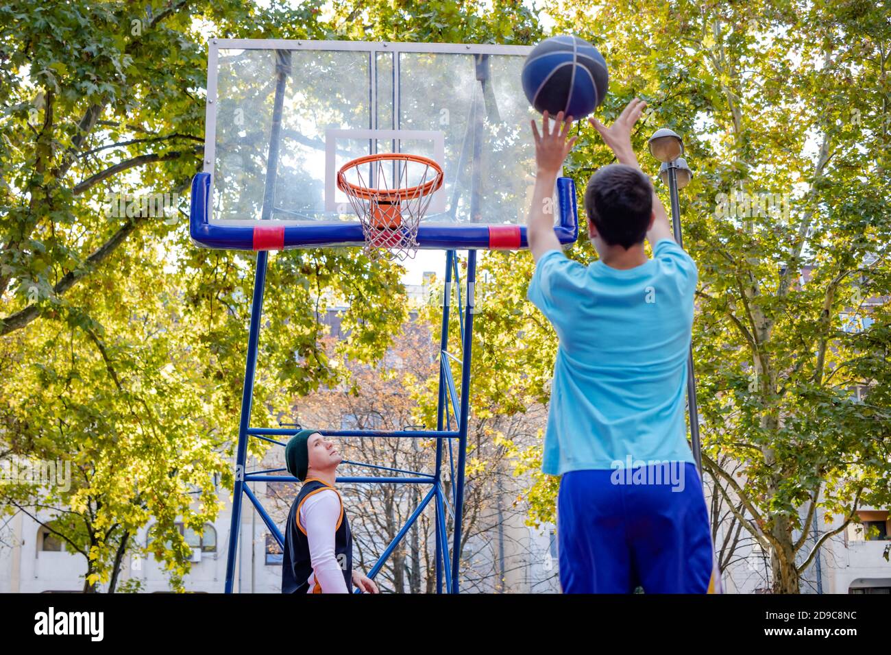 Brothers playing basketball One On One on outdoor court. Shooting at ...