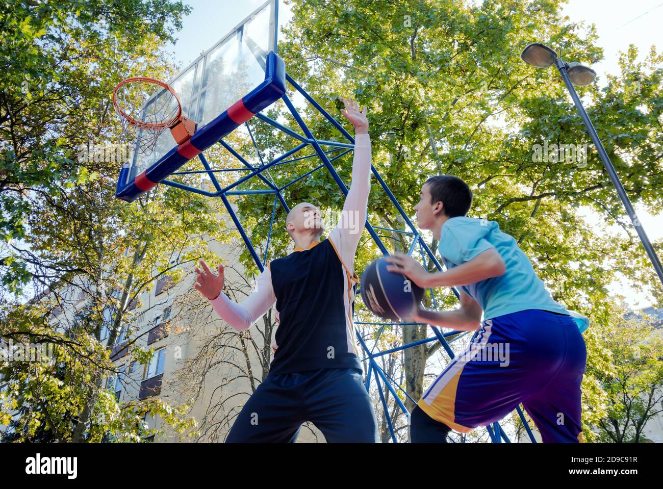Brothers playing basketball One On One on outdoor court. Shooting at ...