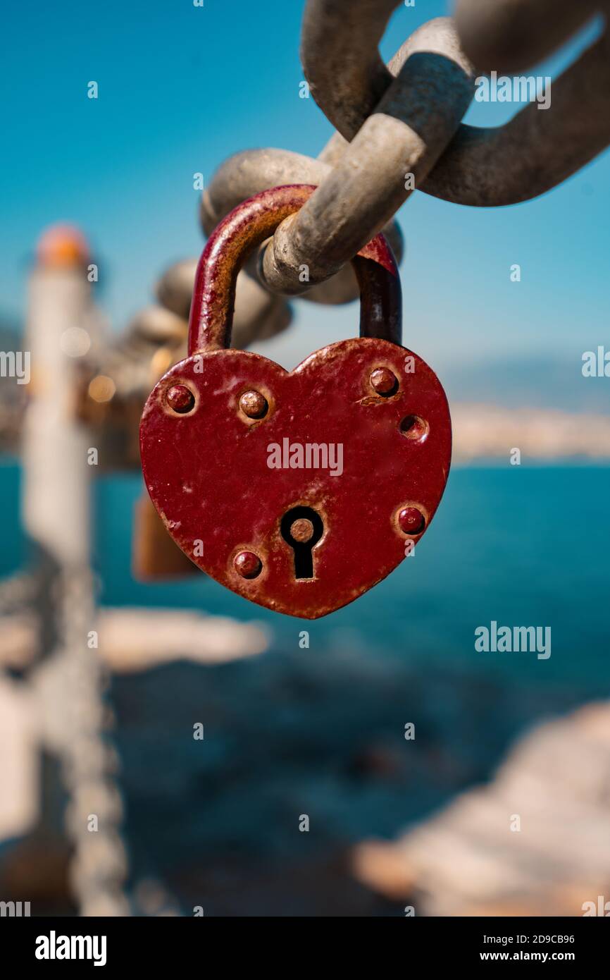 Red heart padlock on chain in front of blue sea and lighthouse, symbol ...