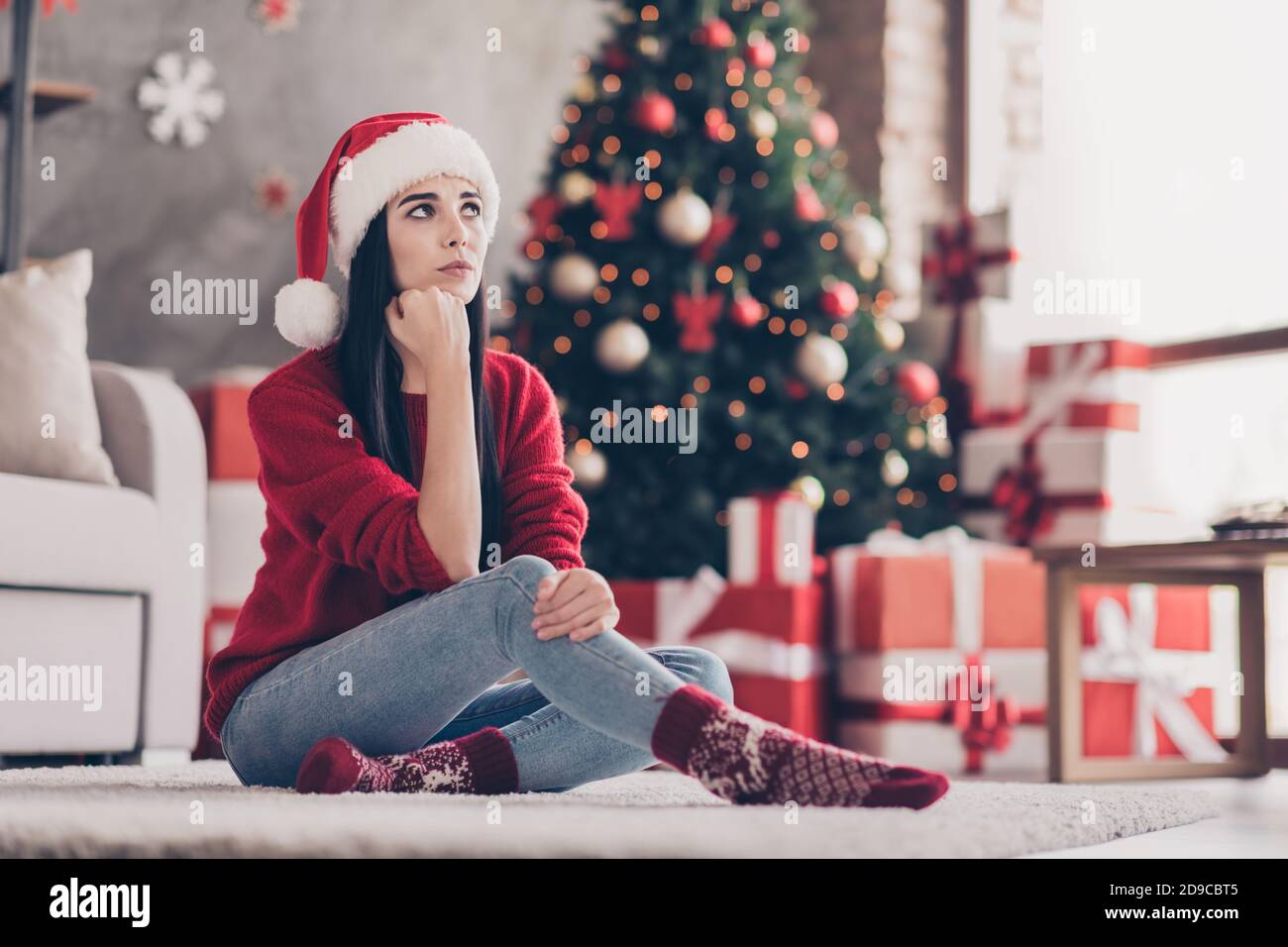Photo of young pensive girl sit floor look up hand chin wear santa ...