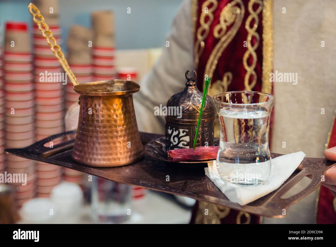 a man serves a tray of traditional Turkish coffee made on the sand in ...