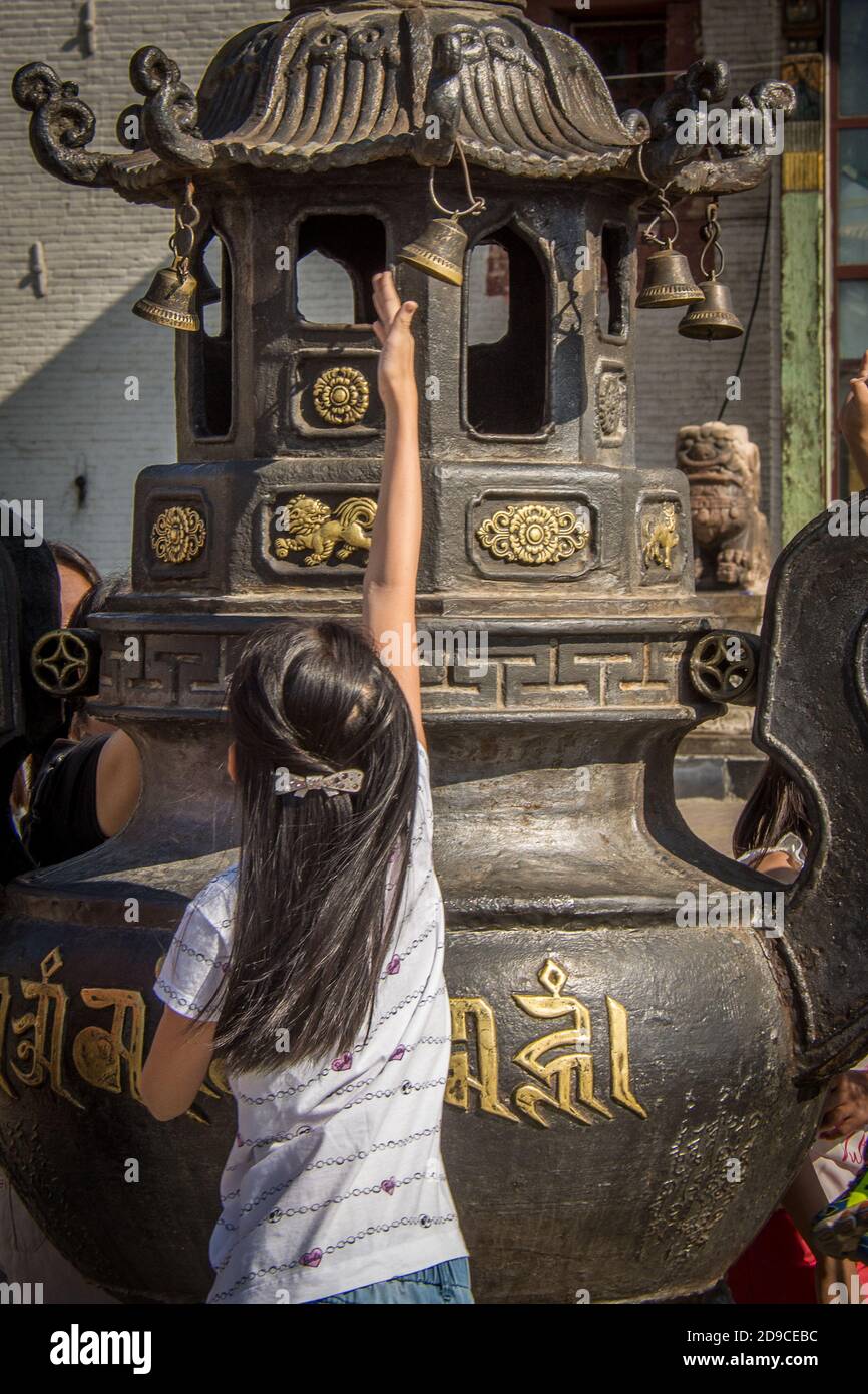 Young girl ringing the bell while entering into the sanctum of a ...