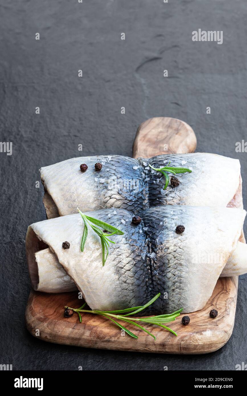 Marinated herring rolls with herbs on black stone background Stock ...