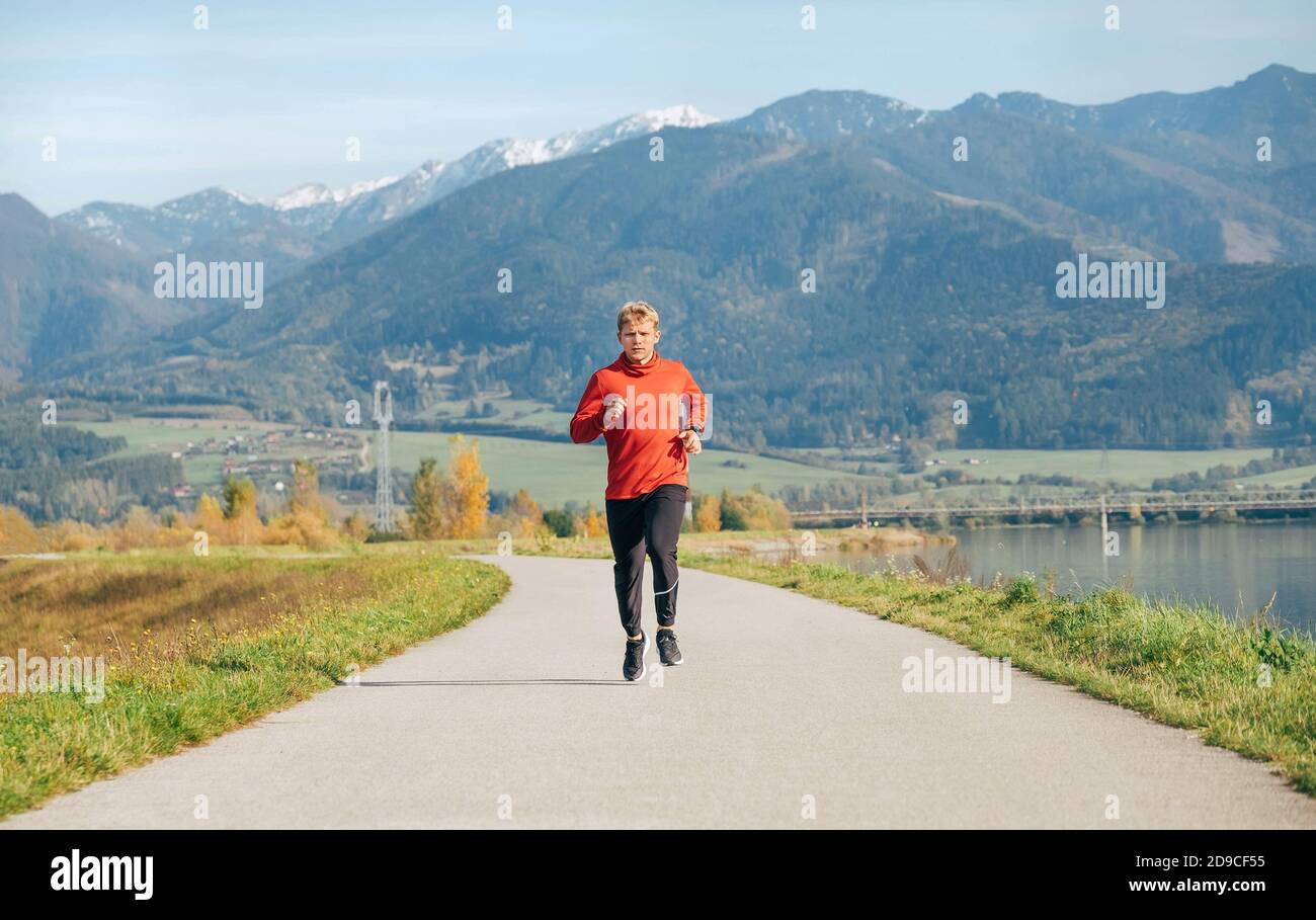 Man dressed in red long sleeve shirt, black running trousers and shoes ...