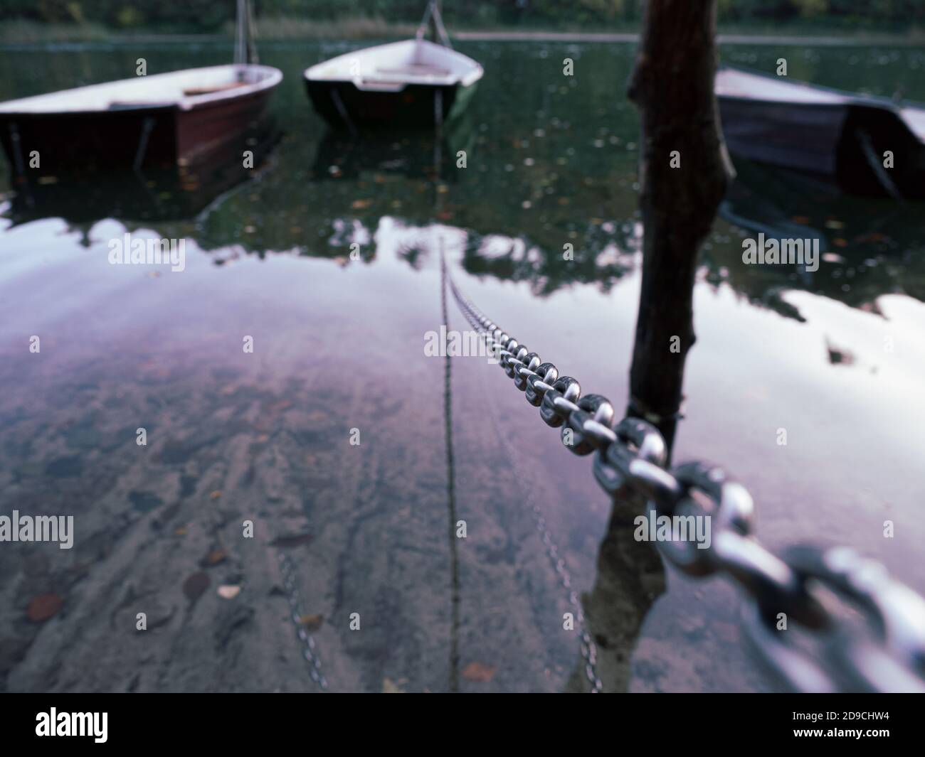 a rowing boat is attached to a steel chain, which floats on a lake ...
