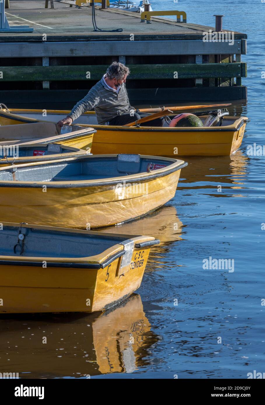 an older or retired man rowing a small yellow boat and coming alongside ...
