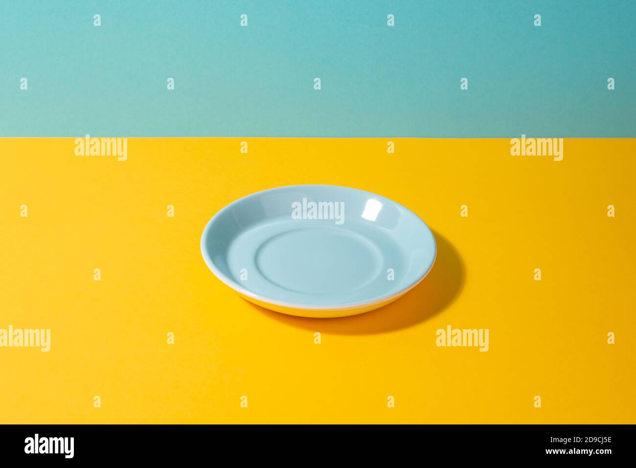 Empty blue tea plate on yellow background Stock Photo - Alamy
