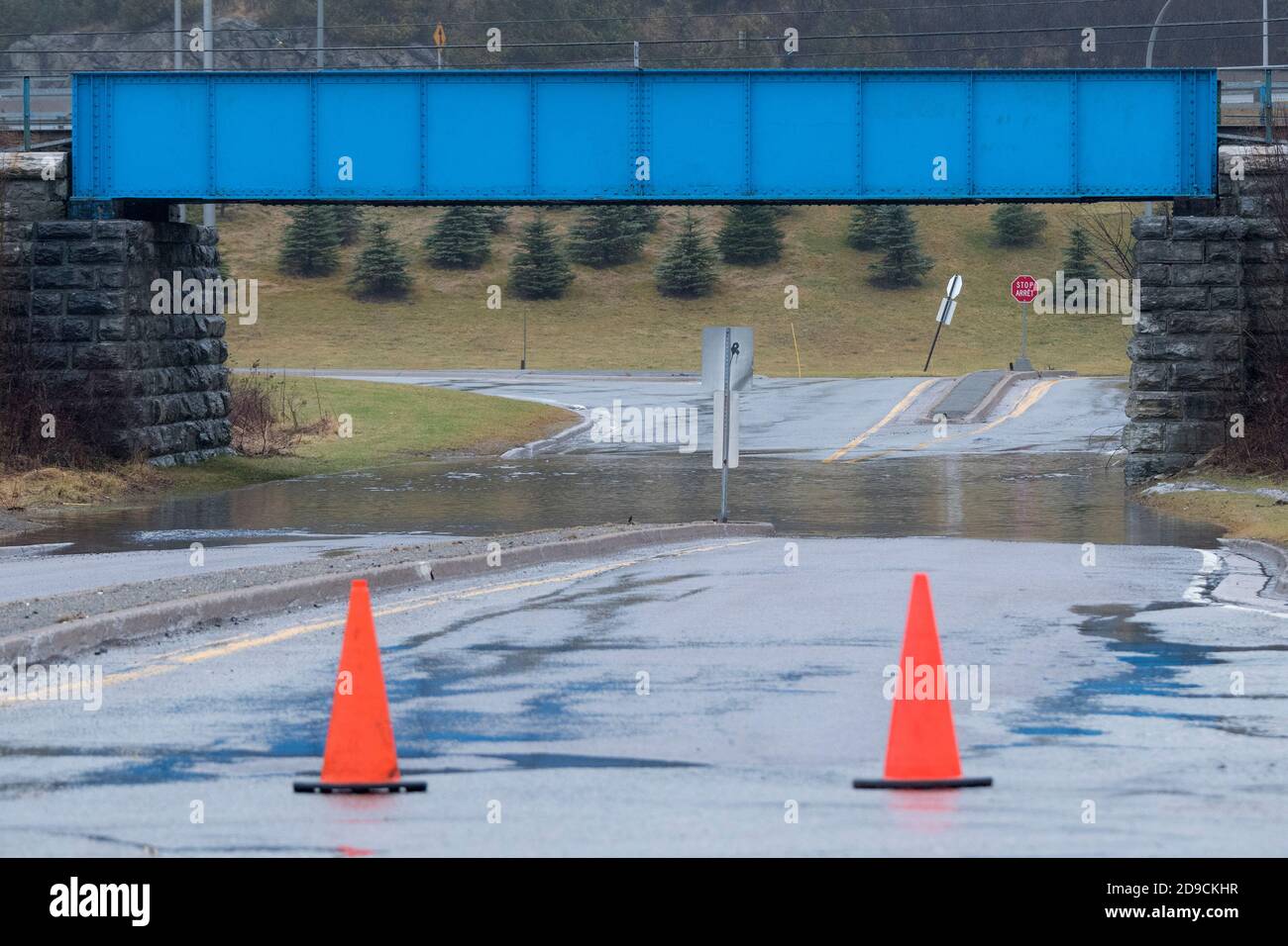 A flooded road under a blue bridge. Orange pylons block the road Stock ...