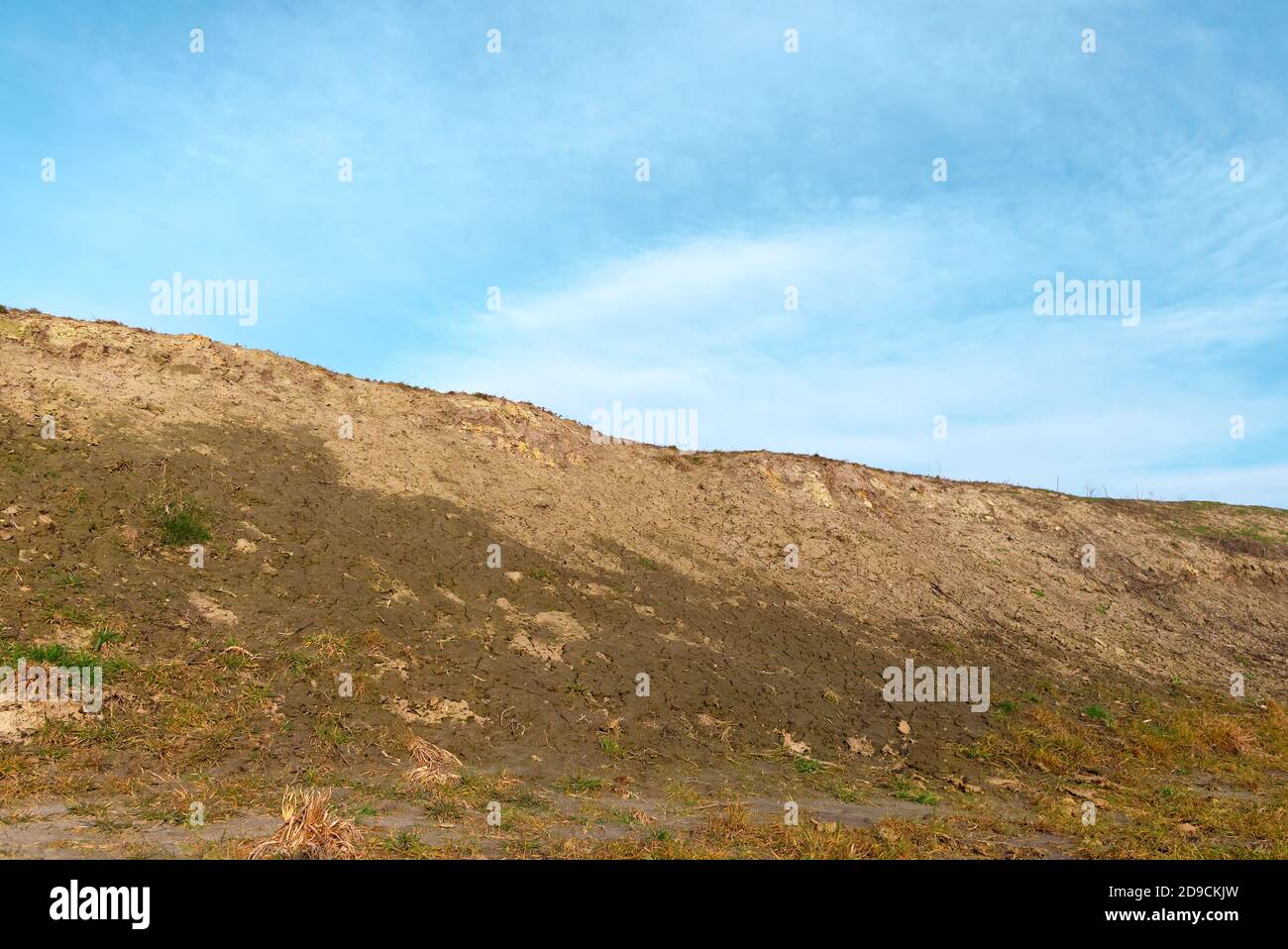 The slope of a clay hill against the backdrop of a beautiful blue sky ...