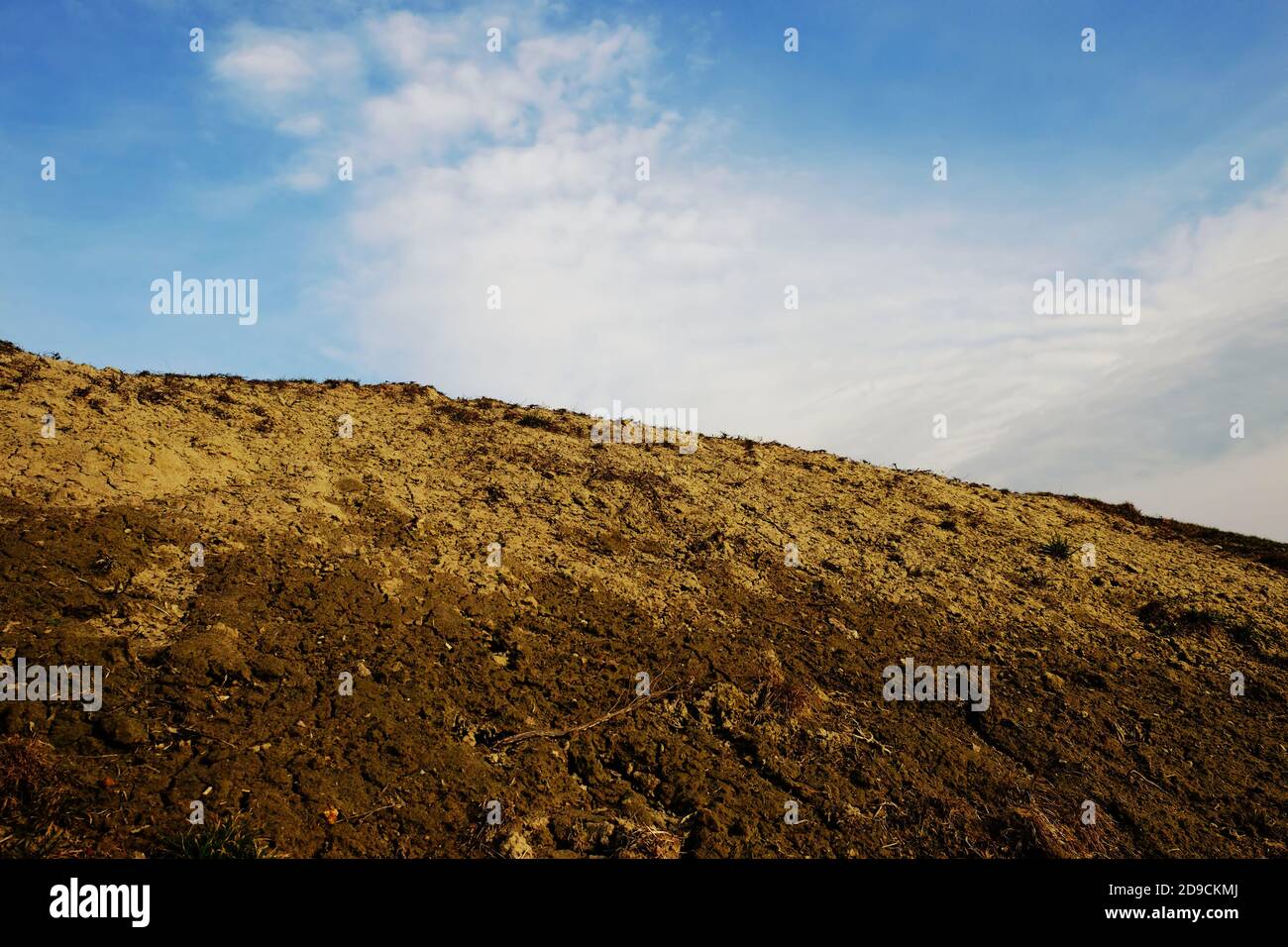 The slope of a clay hill against the backdrop of a beautiful blue sky ...