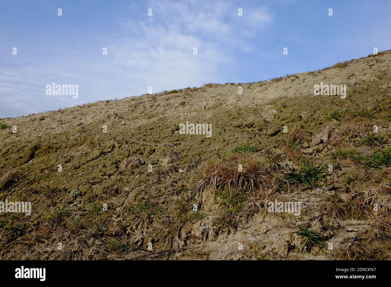 The slope of a clay hill against the backdrop of a beautiful blue sky ...