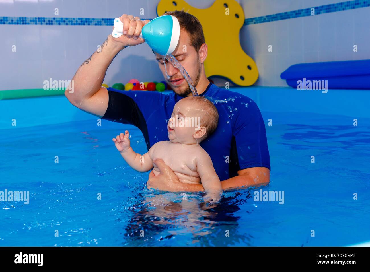 Coach teaches the baby to swim in the pool. baby splash in the water in ...