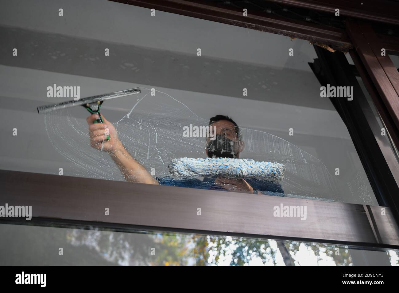 Cleaning the window. A young man with mask on the face cleans and ...
