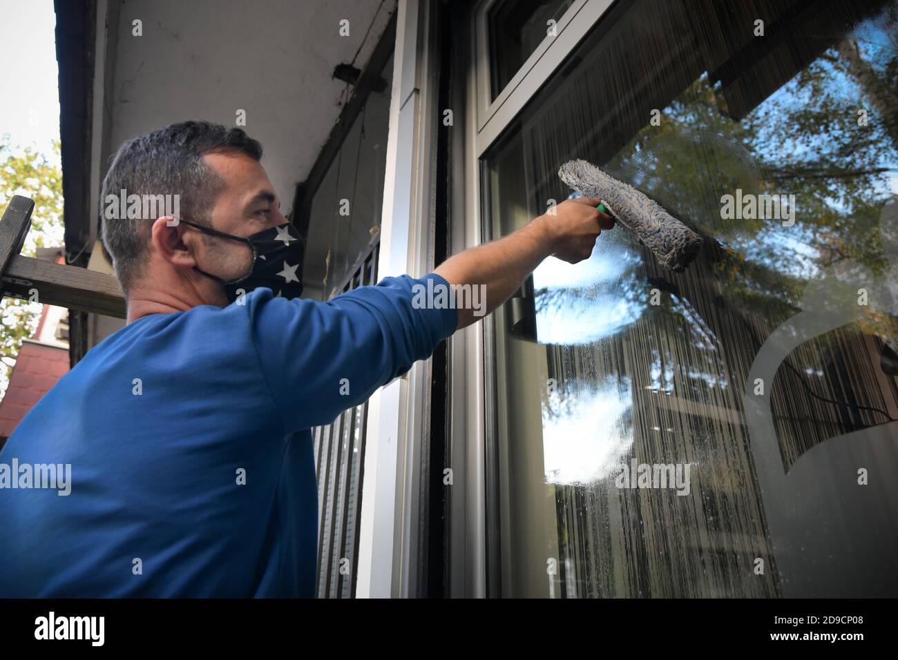 Cleaning the window. A young man with mask on the face cleans and ...