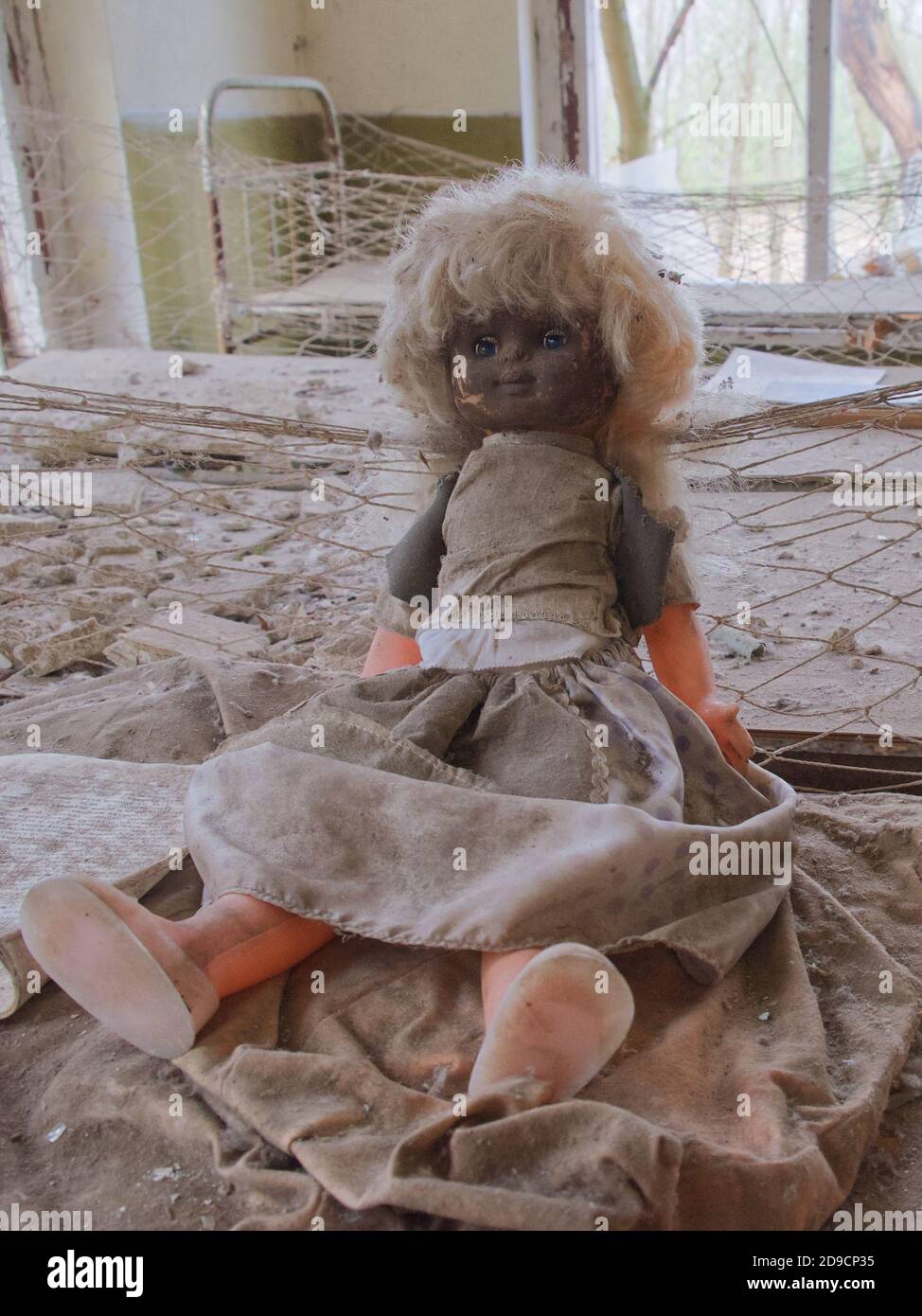 An old doll with a dirty face on a bed in an abandoned kindergarten ...