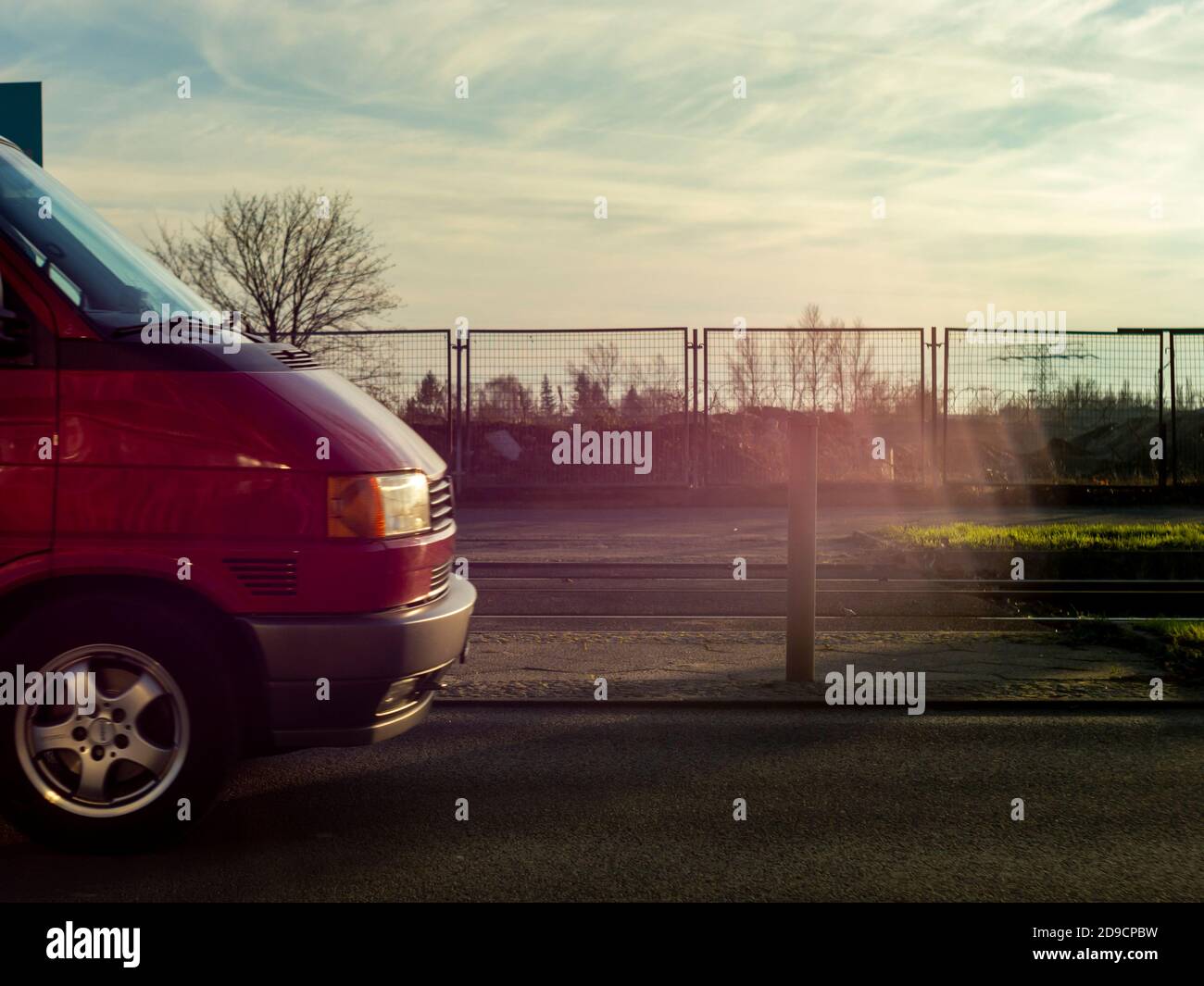 a red van about to drive past in very strong light in an industrial ...