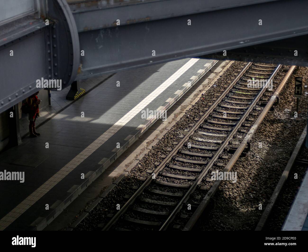 a train platform viewed from a bridge with a single figure standing ...