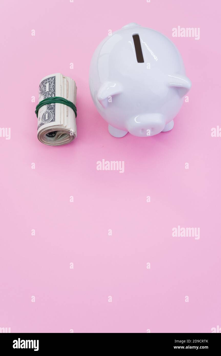 Vertical shot of dollar bills and a piggy bank on a pink surface Stock ...
