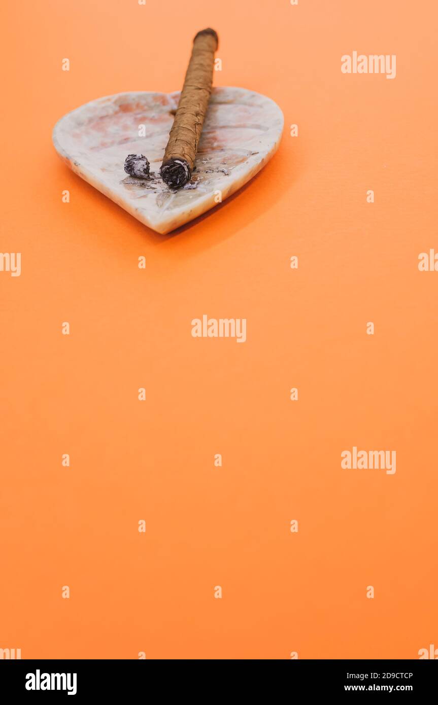 Vertical shot of a cigar on an ashtray on an orange surface Stock Photo ...