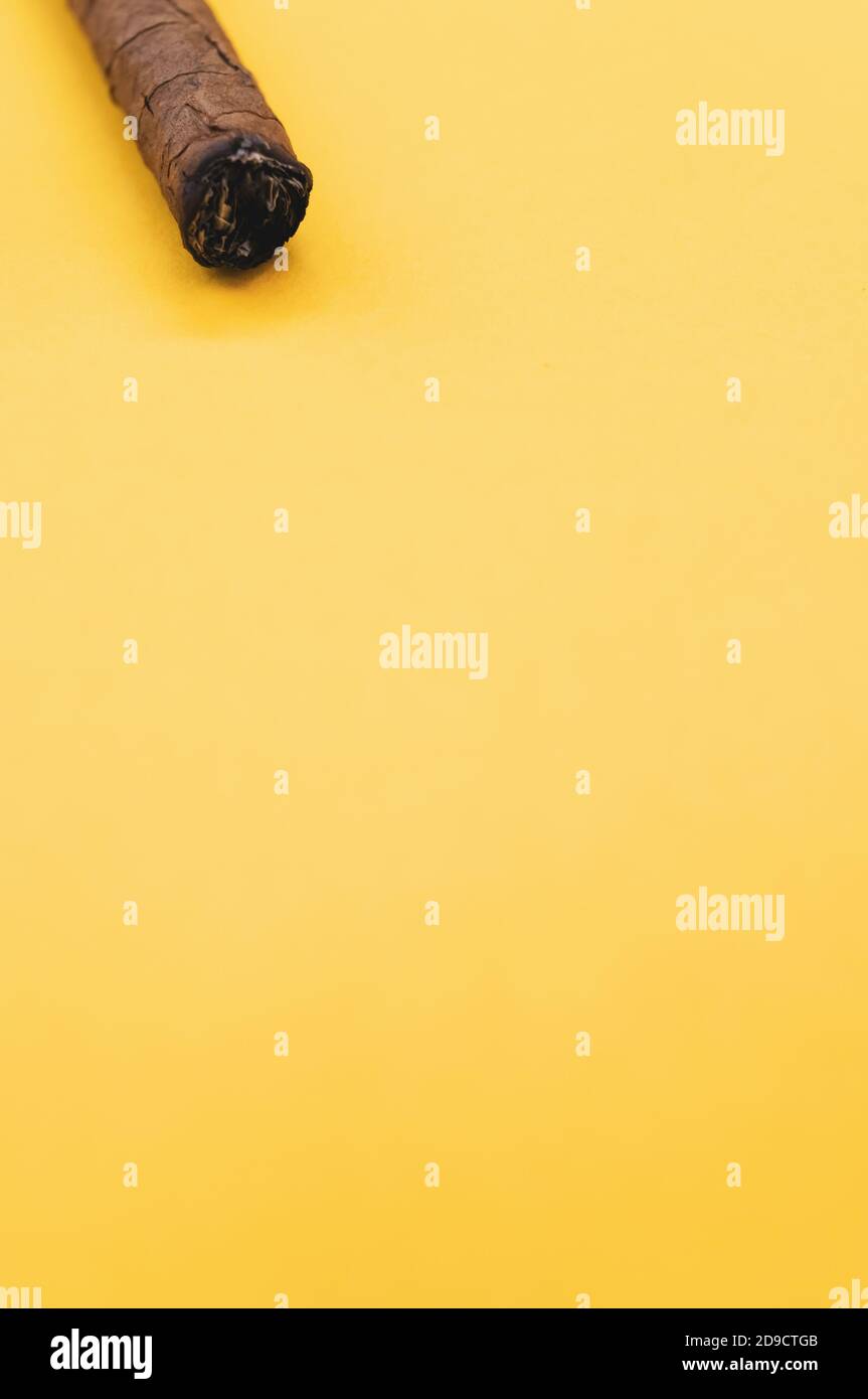 Vertical shot of a burning cigar on a yellow surface Stock Photo - Alamy