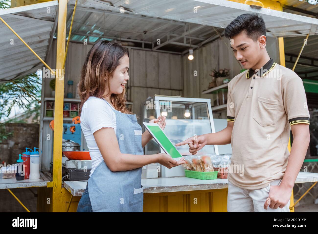 man chooses food a menu that a seller brings. small business asian ...