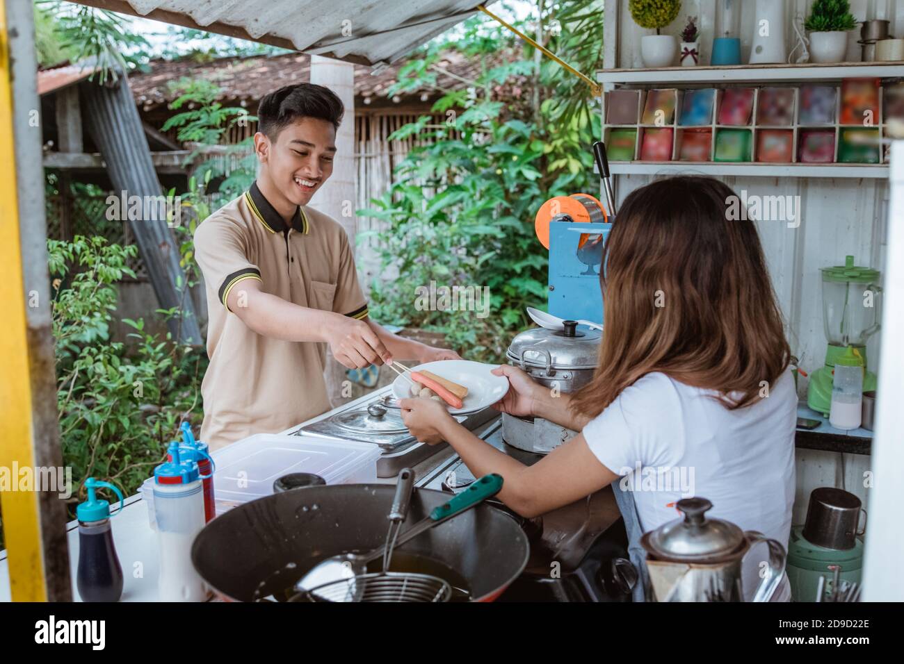 portrait of customer picking his food from small street food seller ...