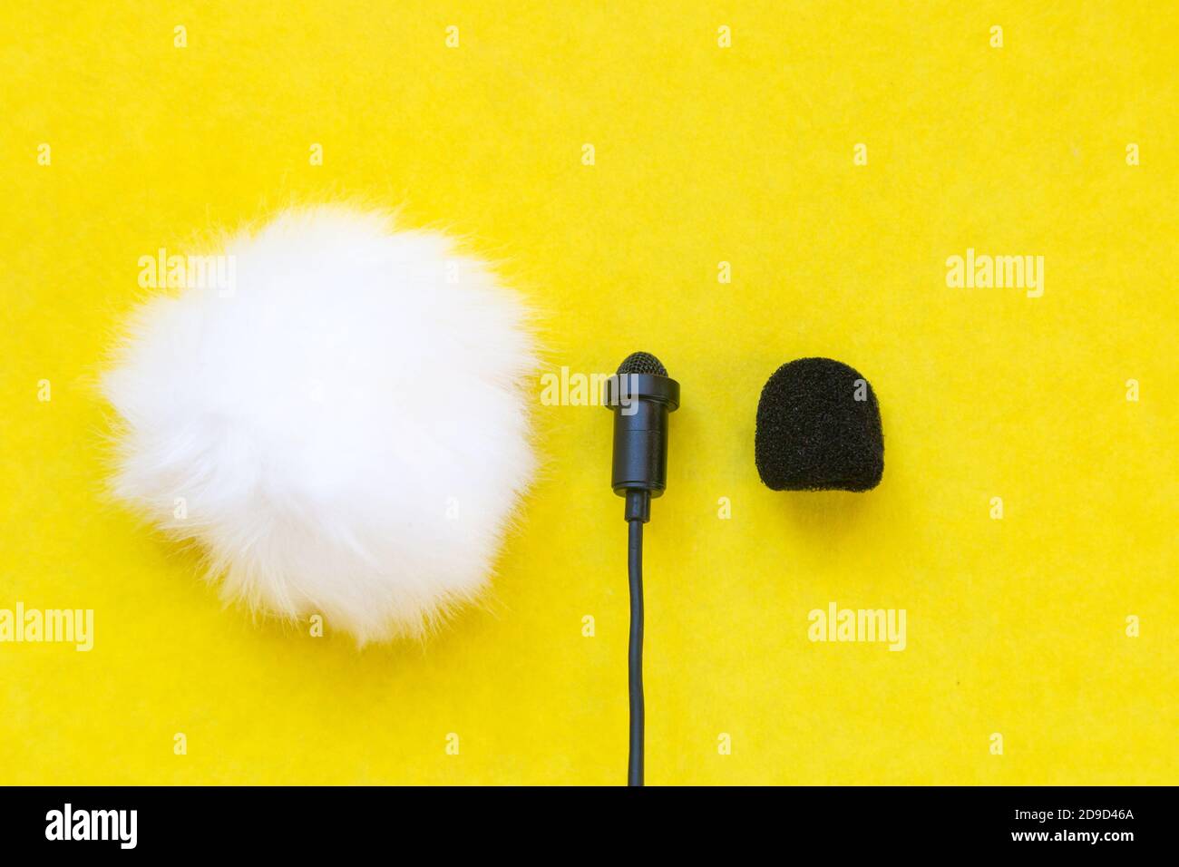 Lavalier small microphone and wind protection on yellow background ...