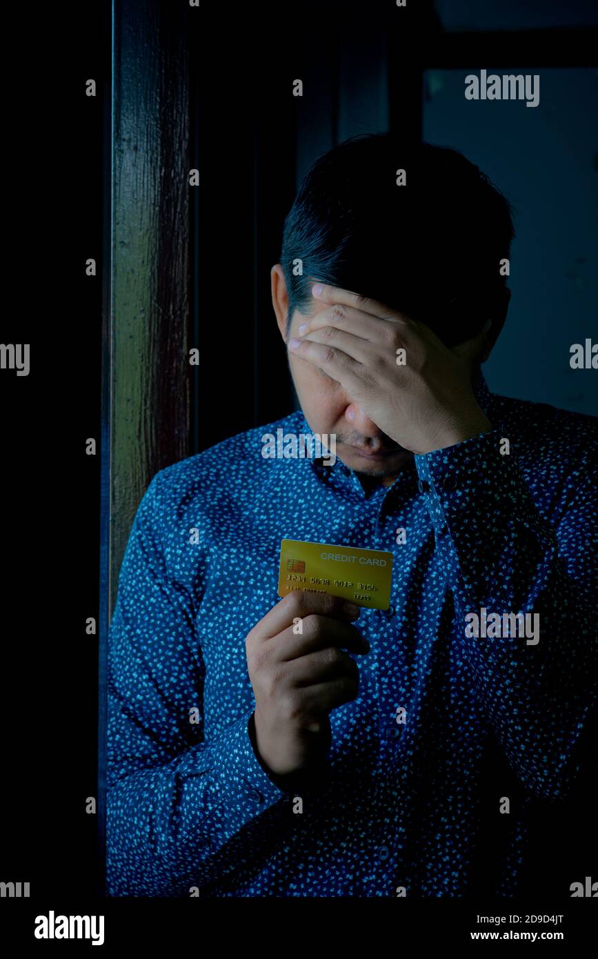 Sad confused and stress man holding credit cards.Low key style Stock ...