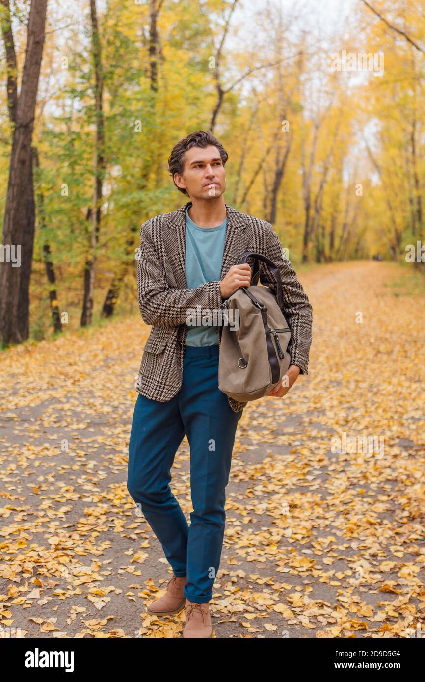 Tall handsome man with a bag on the autumn alley Stock Photo - Alamy