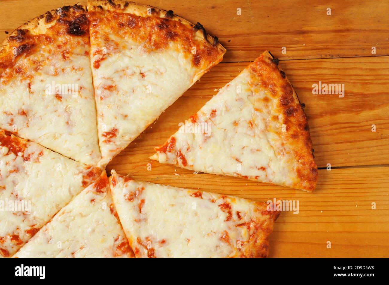 A sliced cheese pizza on a rustic wood counter Stock Photo - Alamy