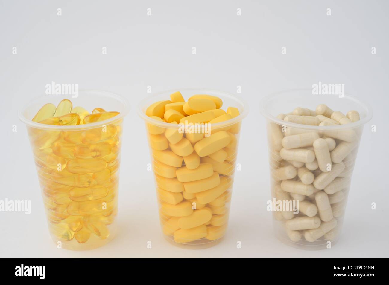 three plastic cups with dietary vitamin tablets pills softgel omega3 ...