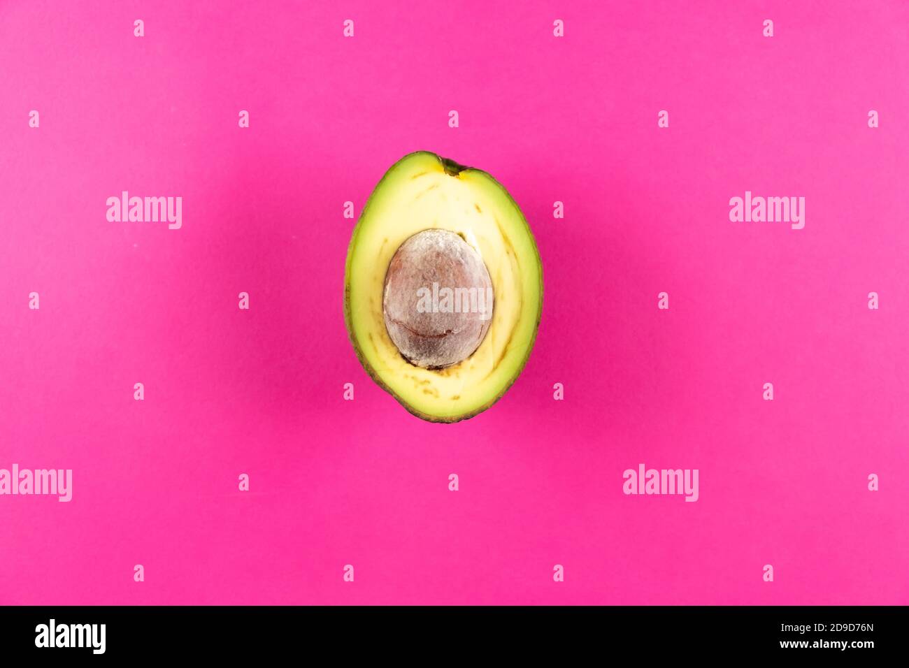 Half fresh avocado fruit on pink background Stock Photo - Alamy