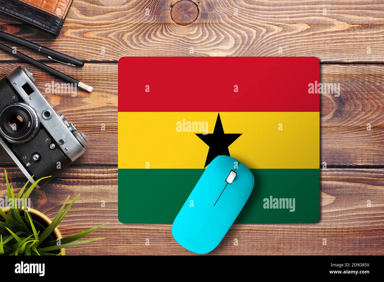 Ghana flag on wooden background with blue wireless mouse on a mouse pad ...