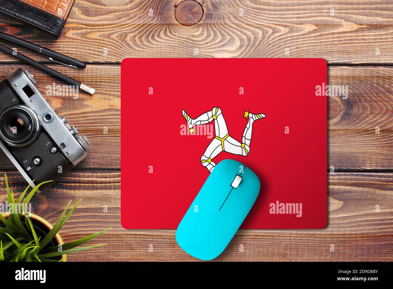 Isle Of Man flag on wooden background with blue wireless mouse on a ...