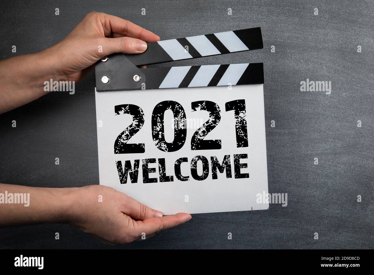 2021 WELCOME. Movie clapper in woman hand. Black chalk board background ...